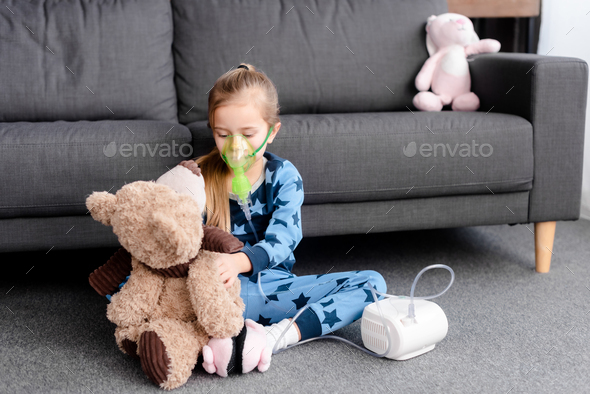 asthmatic child using compressor inhaler and holding teddy bear Stock ...
