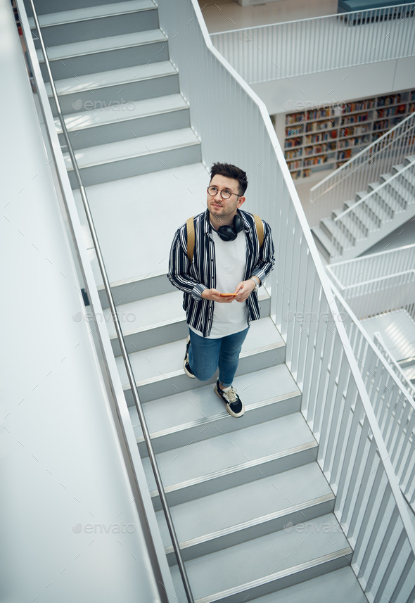Library, staircase and student man walking in a education, learning and ...