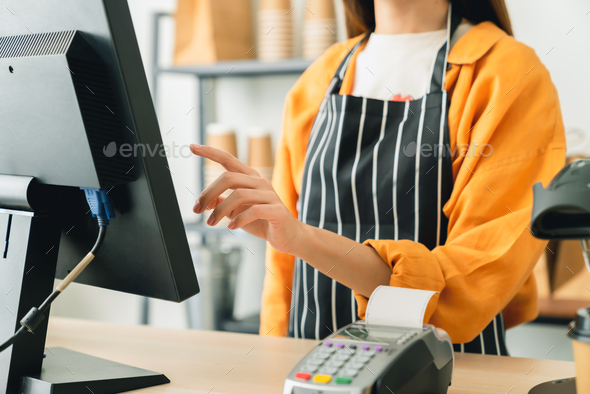 Woman cashier wears an apron and using pos terminal to input orders on ...