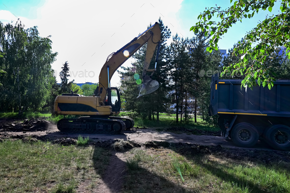 Excavator during earthmoving at open pit on blue sky background ...
