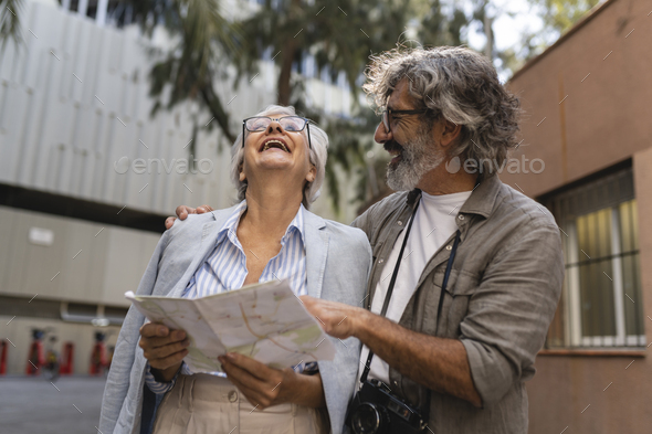 Senior couple holding a map and with a camera - retired travelers are ...
