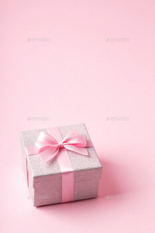 Silver glitter gift box with pink ribbon bow on pink.Valentine's day or ...