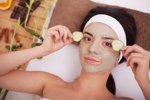 Applying facial mask at woman face at beauty salon Stock Photo by maksymiv