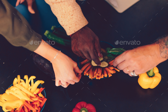 top view of multiethnic hand picking up colored veggie appetizers from ...