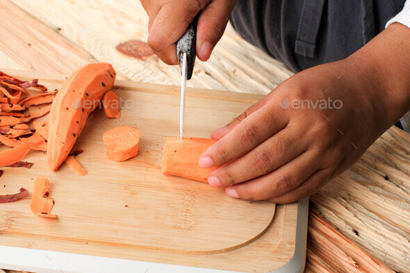 Female Asian Hand Cutting Sweet Potato using Knife on Wooden Table in ...