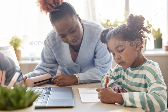 Black young teacher tutoring little girl studying at home Stock Photo ...