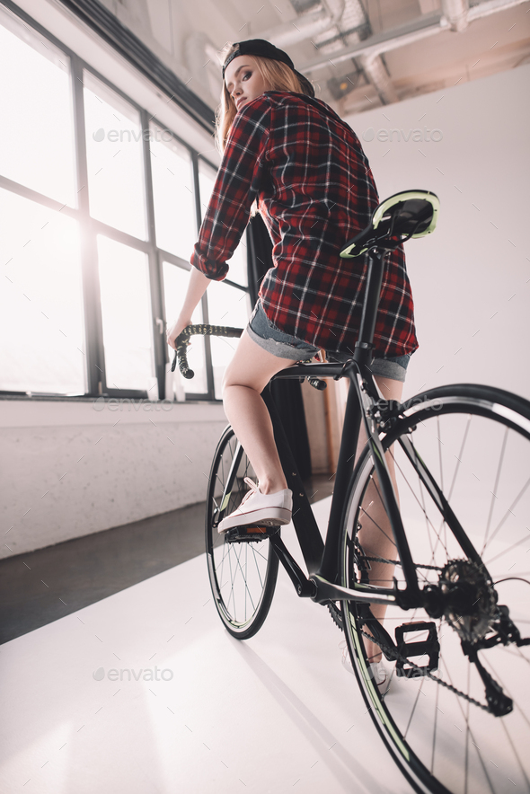 back view of young stylish woman riding bicycle Stock Photo by ...