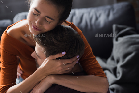 depressed woman embracing head of beloved man while crying at home ...