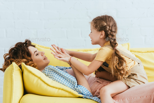 adorable child playing pat-a-cake game with lying nanny while having ...