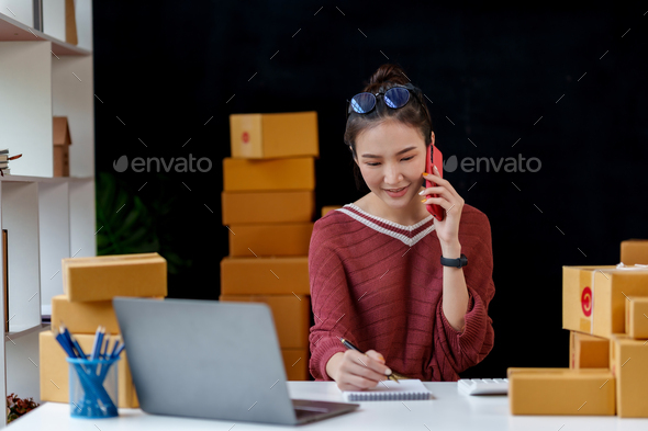 Online business owner Asian woman answering the phone talking to a ...