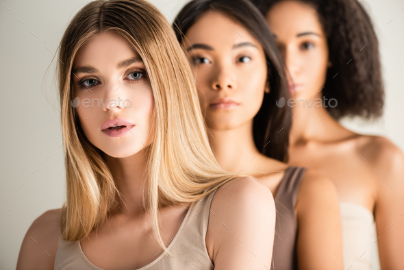 blonde woman looking at camera near african american and asian models ...
