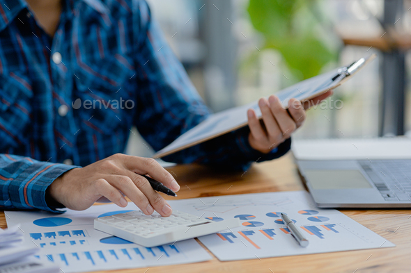 Businessman using a calculator to calculate numbers on a company's ...