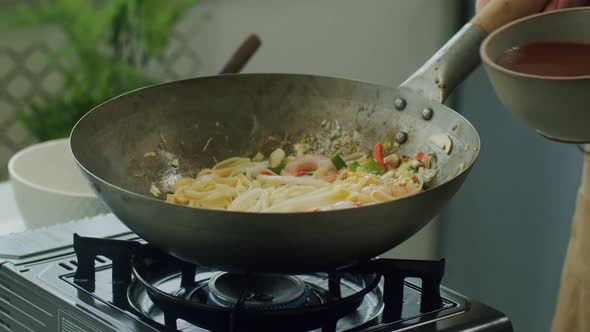 Woman pouring broth into pan with wok noodles, Stock Footage | VideoHive