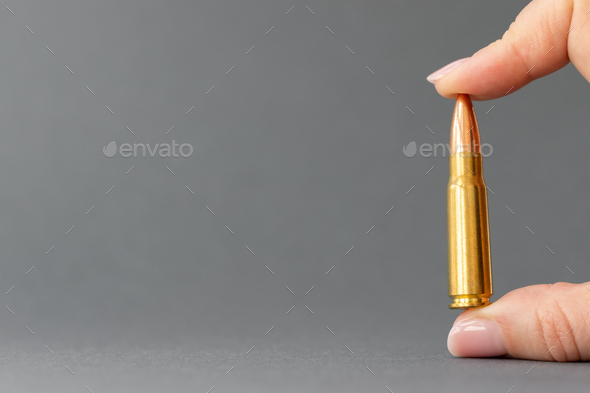 Hand with bullet on gray background. Cartridge 7.62 caliber for ...