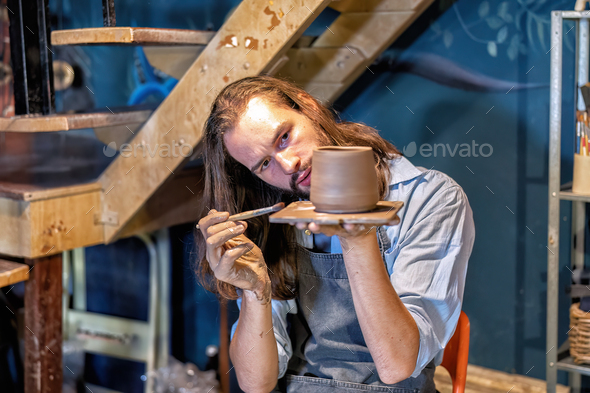 Man hold pot on hand and learn brushing ceramic clay objects in pottery ...