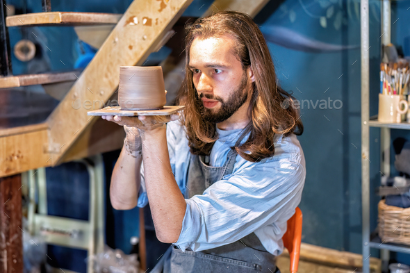 Man hold pot on hand and learn brushing ceramic clay objects in pottery ...