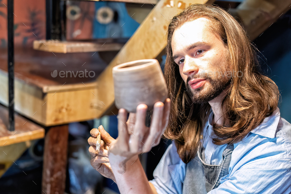 Man hold pot on hand and learn brushing ceramic clay objects in pottery ...