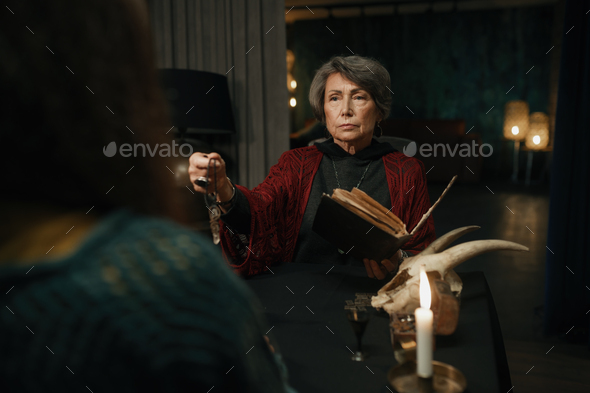 Gypsy reading spell for client using witchcraft book and magic pendulum ...