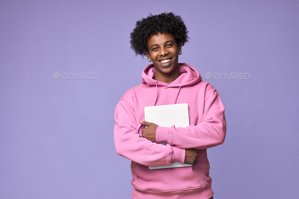 Happy African teen student holding laptop isolated on purple background ...