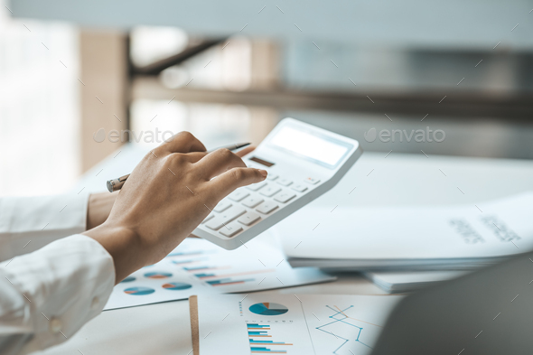 Businessman using a calculator to calculate numbers on a company's ...