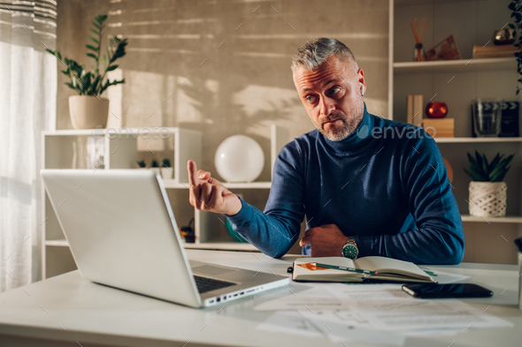 Middle aged man showing middle finger to a laptop screen while working ...