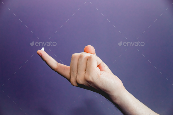 Cream on the index finger of a white hand on a purple background Stock ...