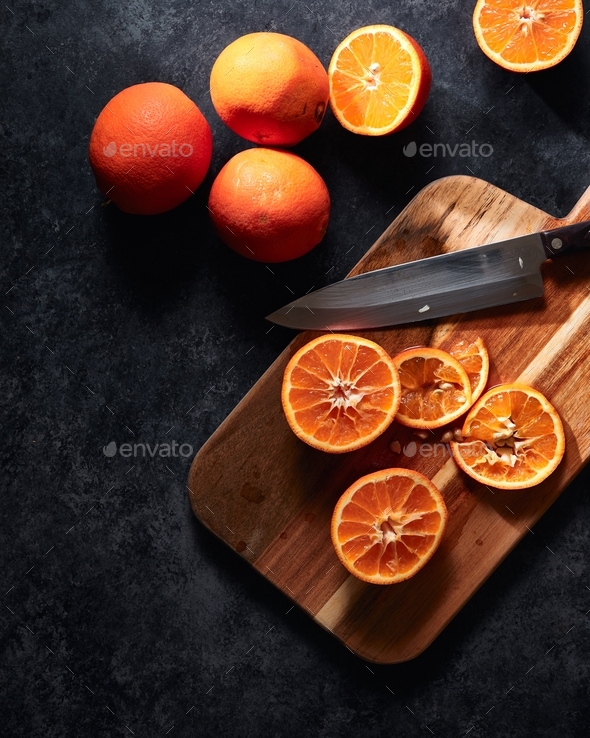 Vertical shot of sliced oranges and a knife on a chopping board on a ...
