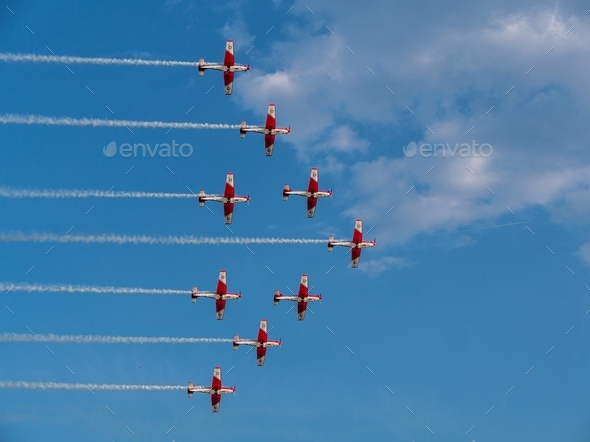 Red jets performing an airshow while leaving white tracks in the sky ...