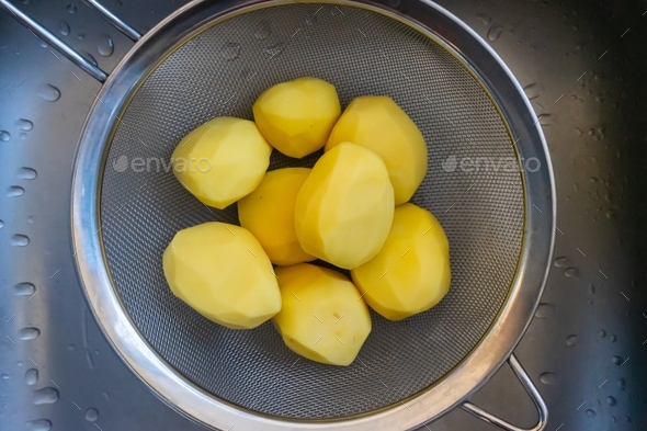 High angle shot of raw peeled potatoes in a strainer in the kitchen ...