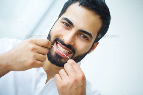 Teeth Care. Beautiful Smiling Man Flossing Healthy White Teeth. High ...