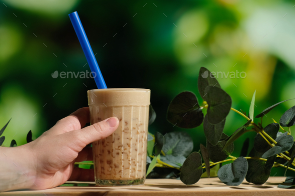 Hand holding glass of bubble tea outdoors. Stock Photo by Meteoritka