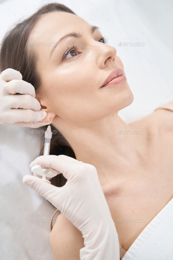 Woman receiving ear injection in cosmetology clinic Stock Photo by ...