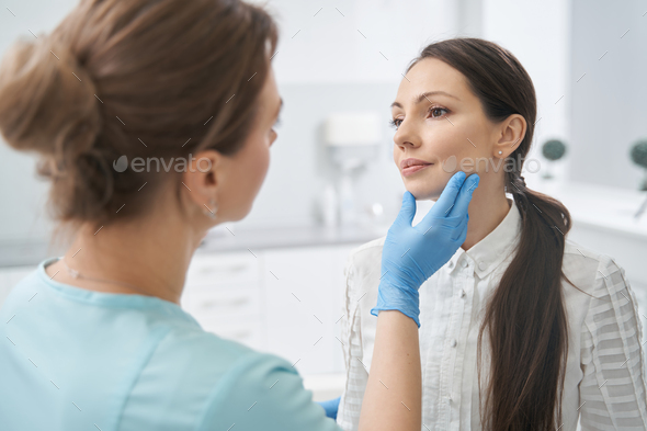 Aesthetic therapist checking woman face skin in cosmetology clinic ...