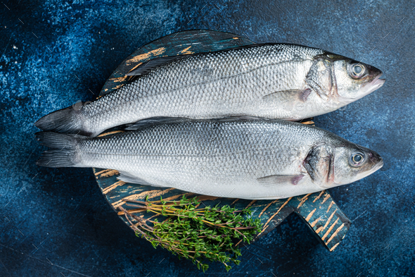Uncooked Raw Sea Bass fish, Seabass with thyme. Blue background. Top ...