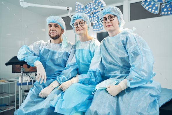 Medic sitting with female co-workers on operation bed Stock Photo by ...