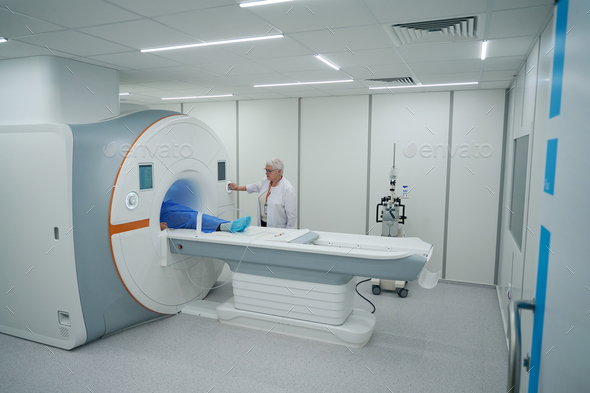 Elderly diagnostician examines a patient on an MRI machine Stock Photo ...