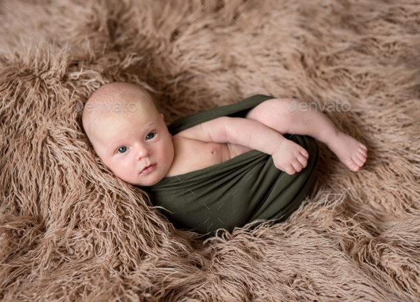 Little cute baby lying on the light brown bedcover Stock Photo by tan4ikk