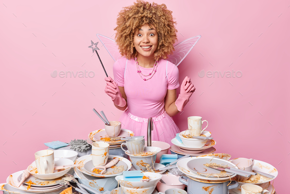 Positive curly haired young female fairy wears dress and wings holds ...