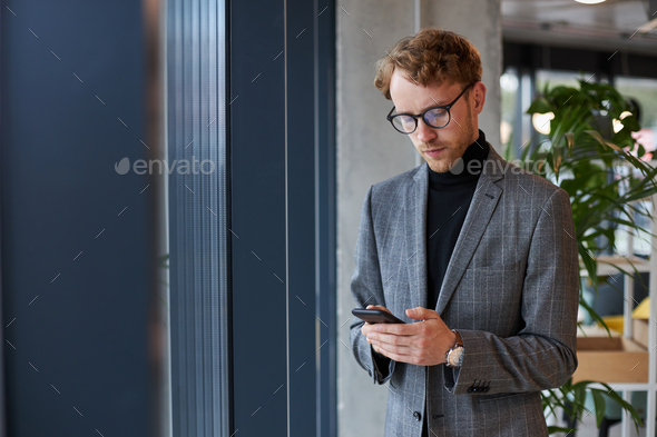 Multitasking male entrepreneur in formal wear, checking new mobile app ...