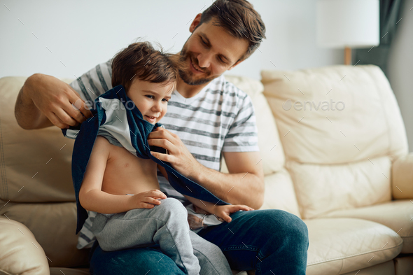 Happy little boy getting dressed with help of his father at home. Stock ...