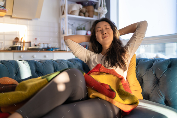 Serene housewife lady sitting on sofa, feeling tired, dozing, holding ...