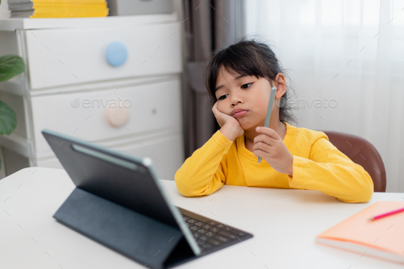 Little Asian girl sitting alone and looking out with a bored face ...