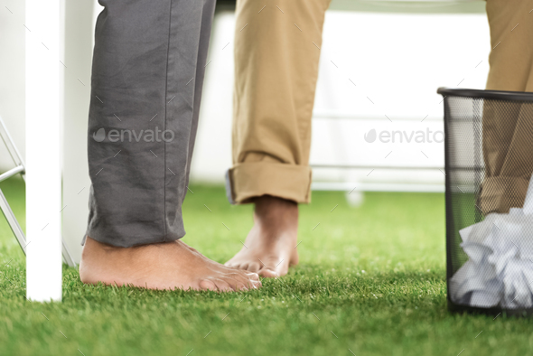 Partial view of barefoot businessmen sitting at table and working on ...