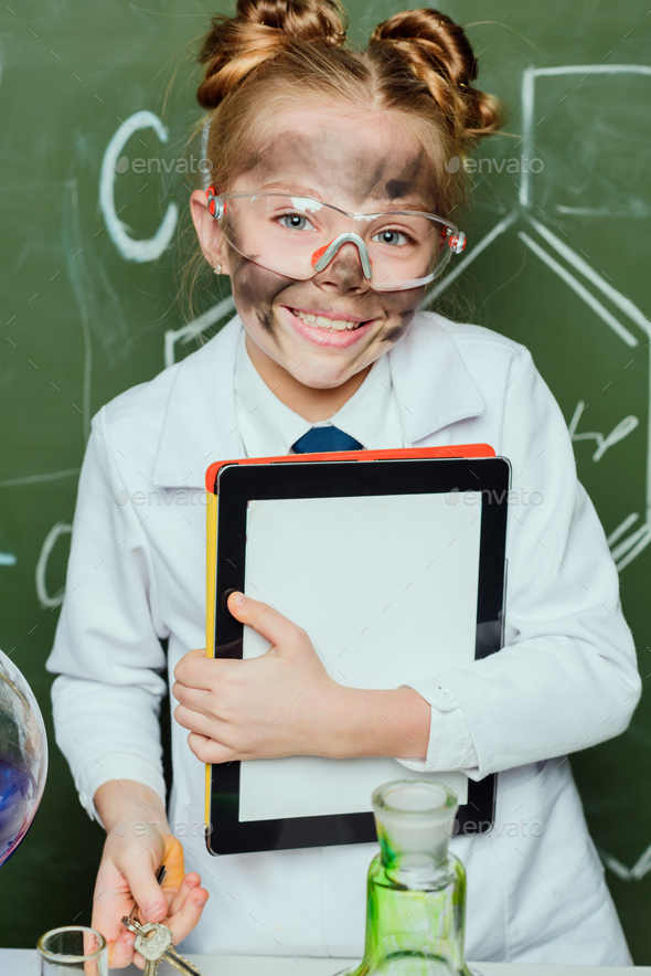 portrait of little girl in lab coat holding digital tablet in science ...