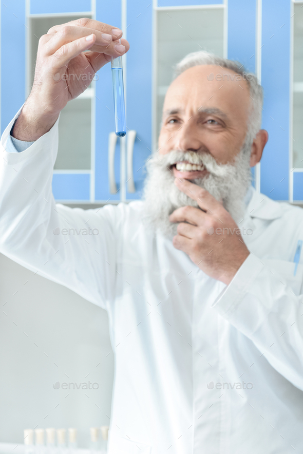 smiling senior bearded scientist in white coat holding tube with ...