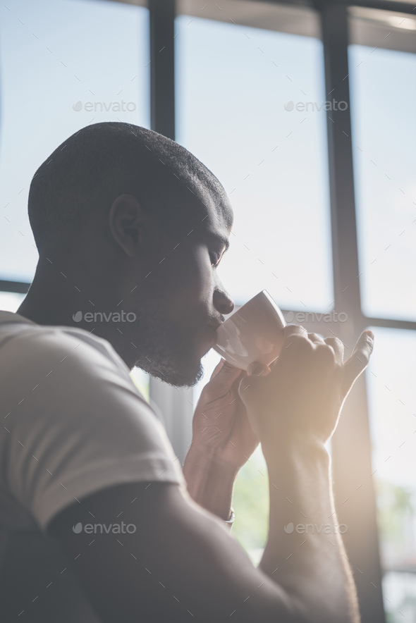 Handsome african american man having his morning coffee at home with ...