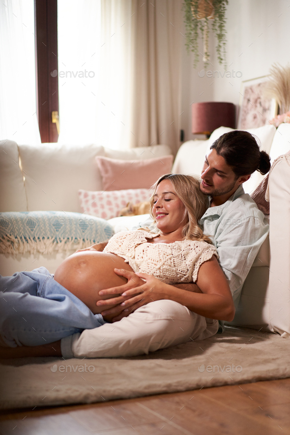 Vertical Pregnancy belly Caucasian husband and wife hugging at home ...