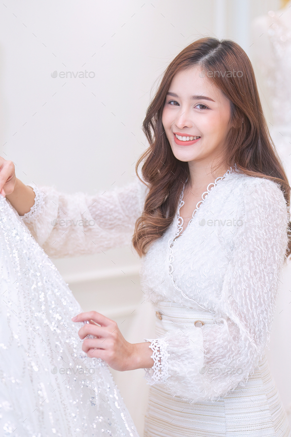 Women happy see many wedding dresses on shelf and in hands choose ...