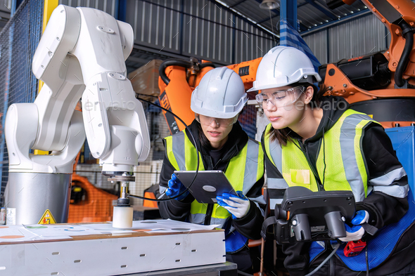 Women engineer team together at work in modern advanced robot welding ...