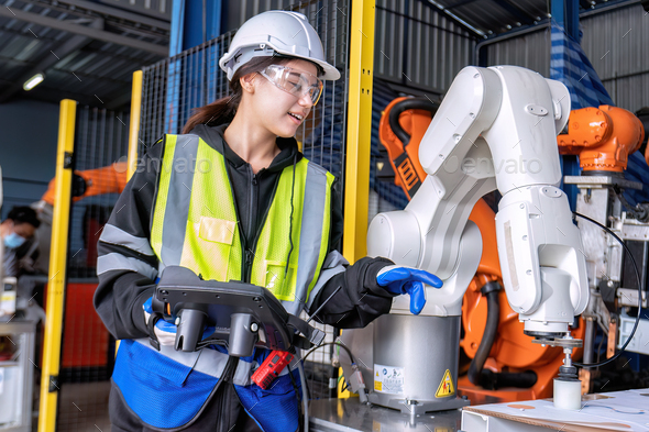 Young female asian service engineer holding robot controller operate ...